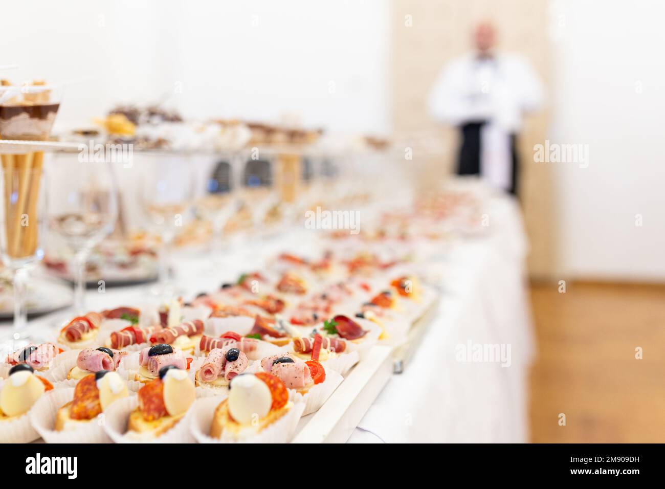 Various canapes appetizers served on buffet table. Waiter in the ...