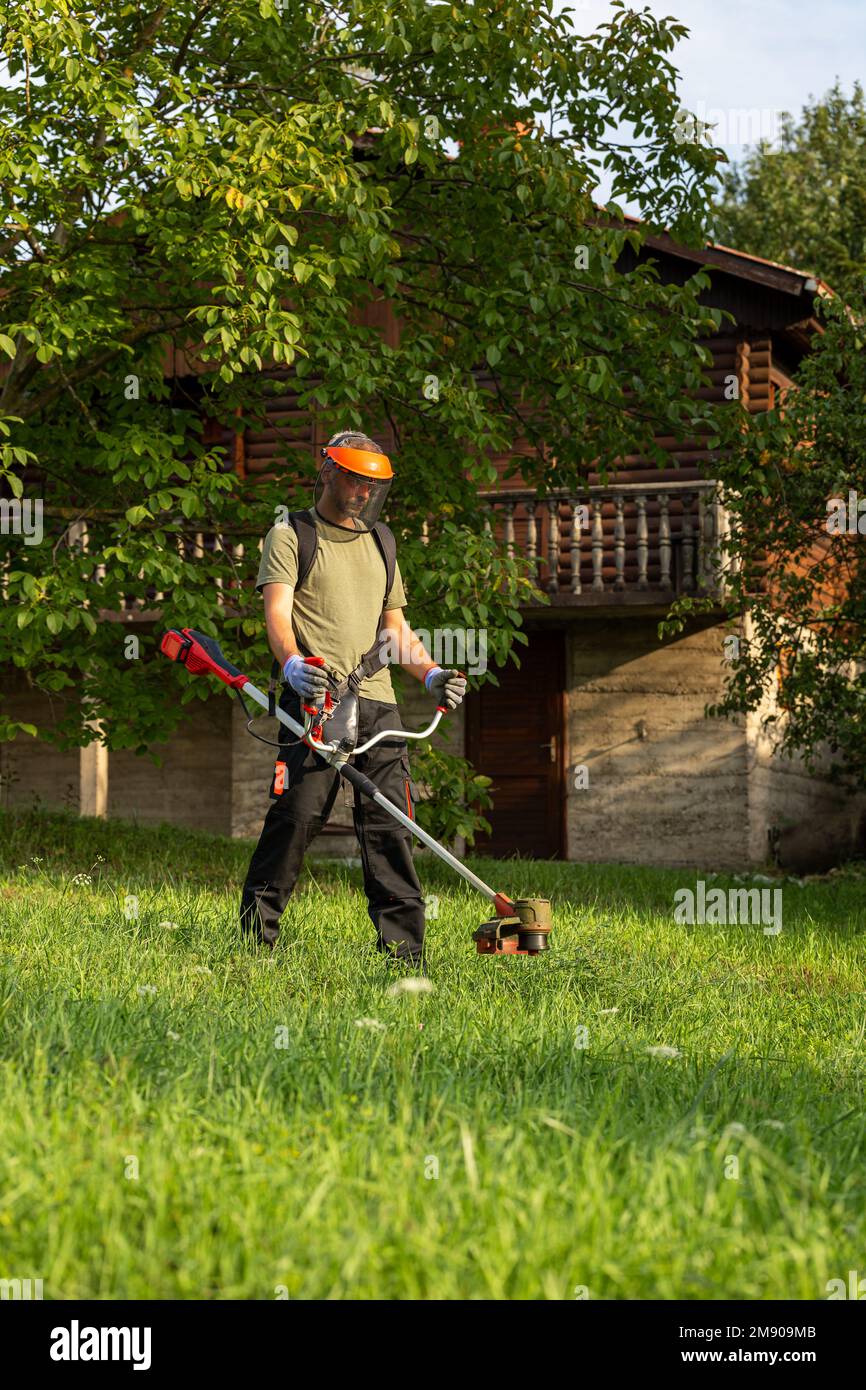 Landscape maintenance concept. Man cutting grass in yard by using ...