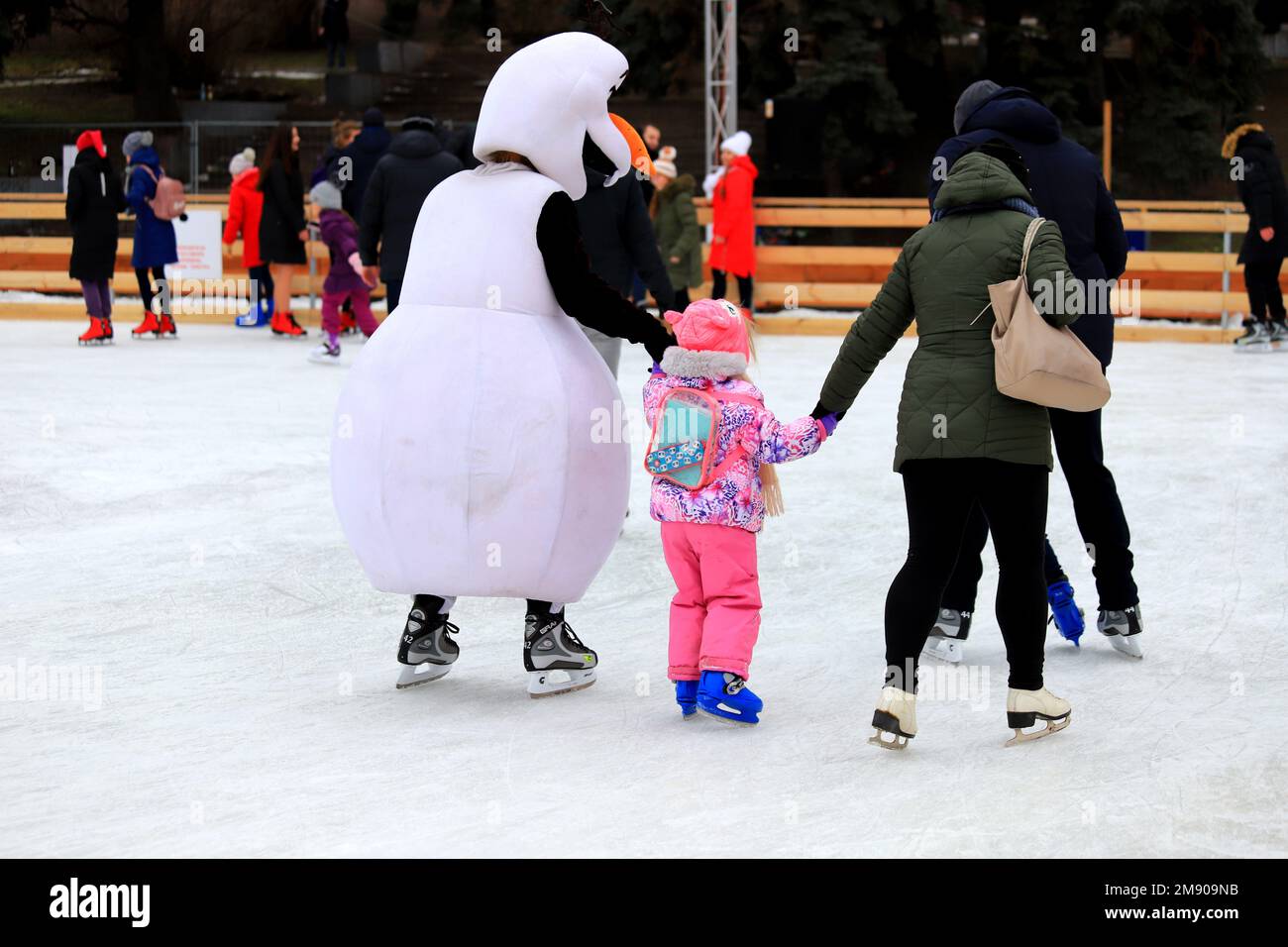 Ice rink in winter. Funny snowman teaches child to skate. Sports ...