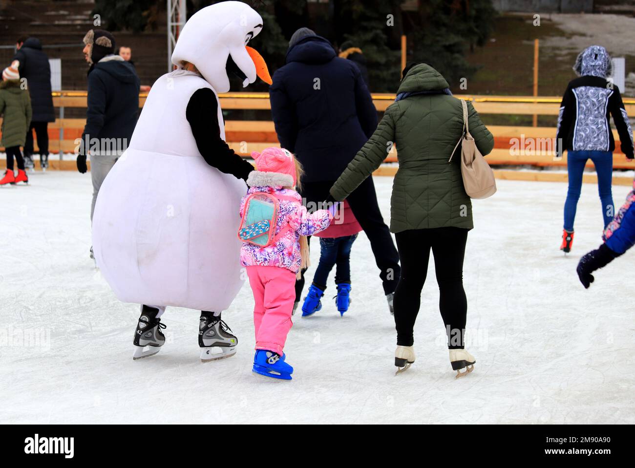 Ice rink in winter. Funny snowman teaches child to skate. Sports ...
