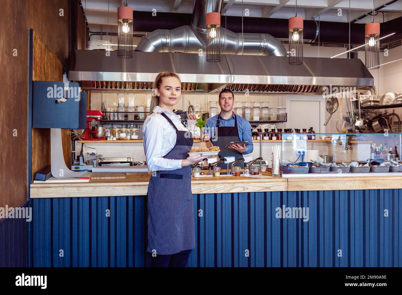Smiling small business owners serving food in new fast food restaurant ...