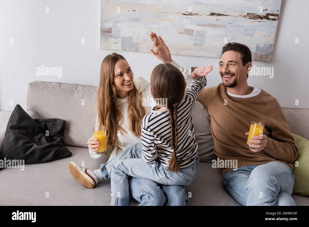 kid giving high five to cheerful mother near happy father sitting with ...