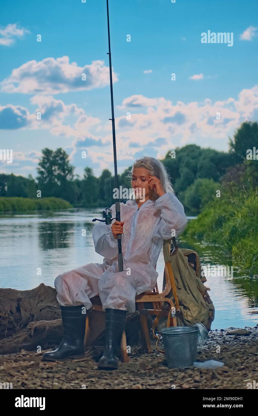 Beautiful woman fisherman is resting on the river. Female is fishing ...