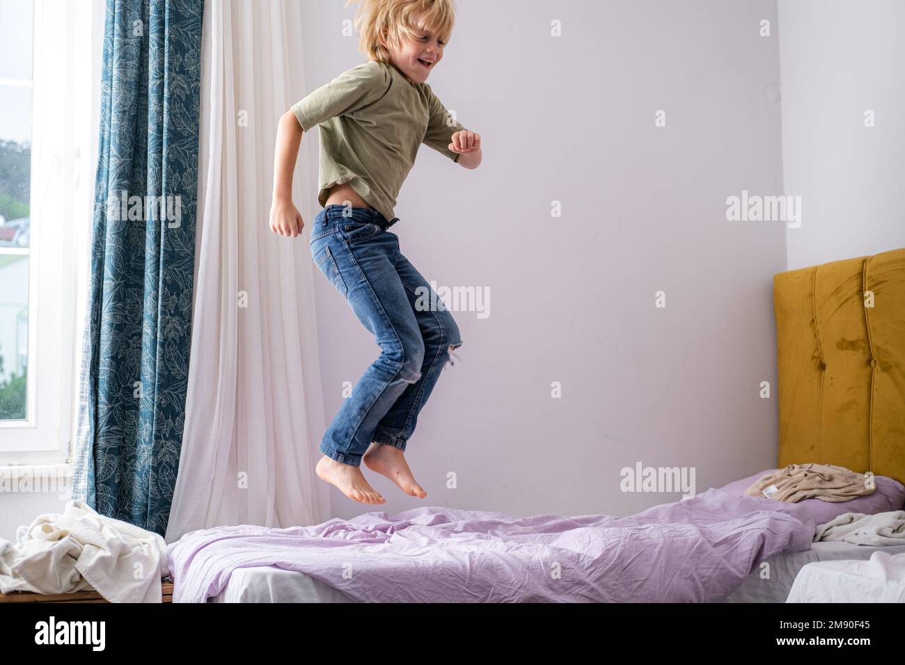 boy having fun, jumping on bed in messy childrens room, kid playing ...