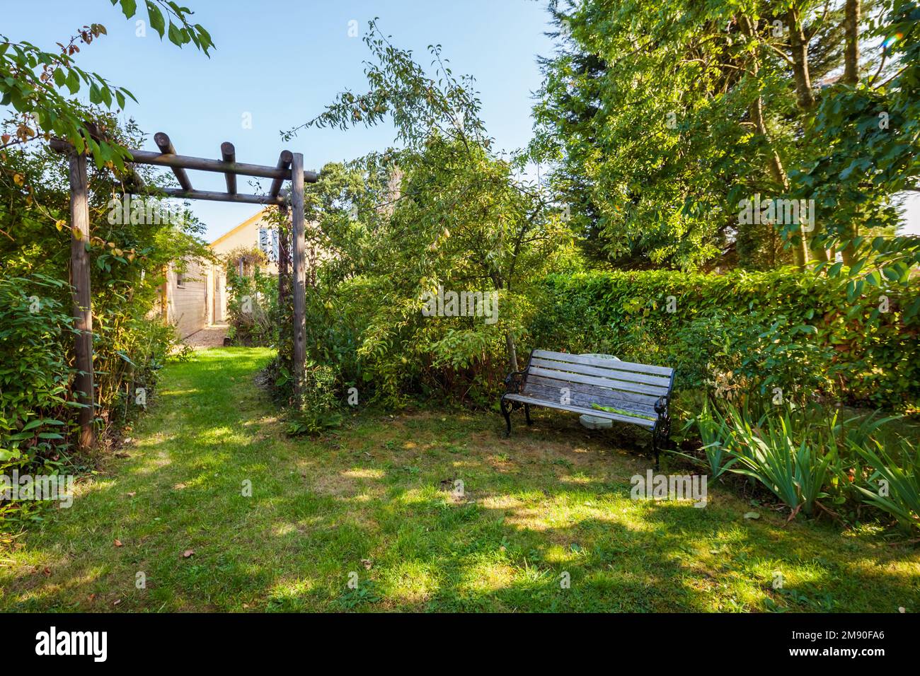 Surburban landscaped gardens with bench and pergola with sunlight and ...