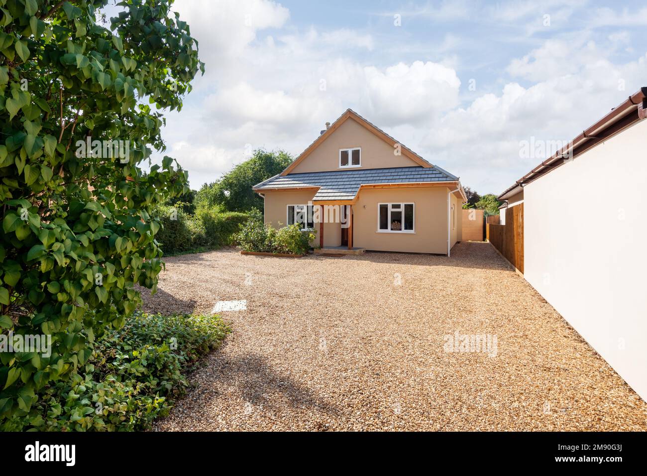 Detached house with large gravel driveway bathed in sunshine viewed ...