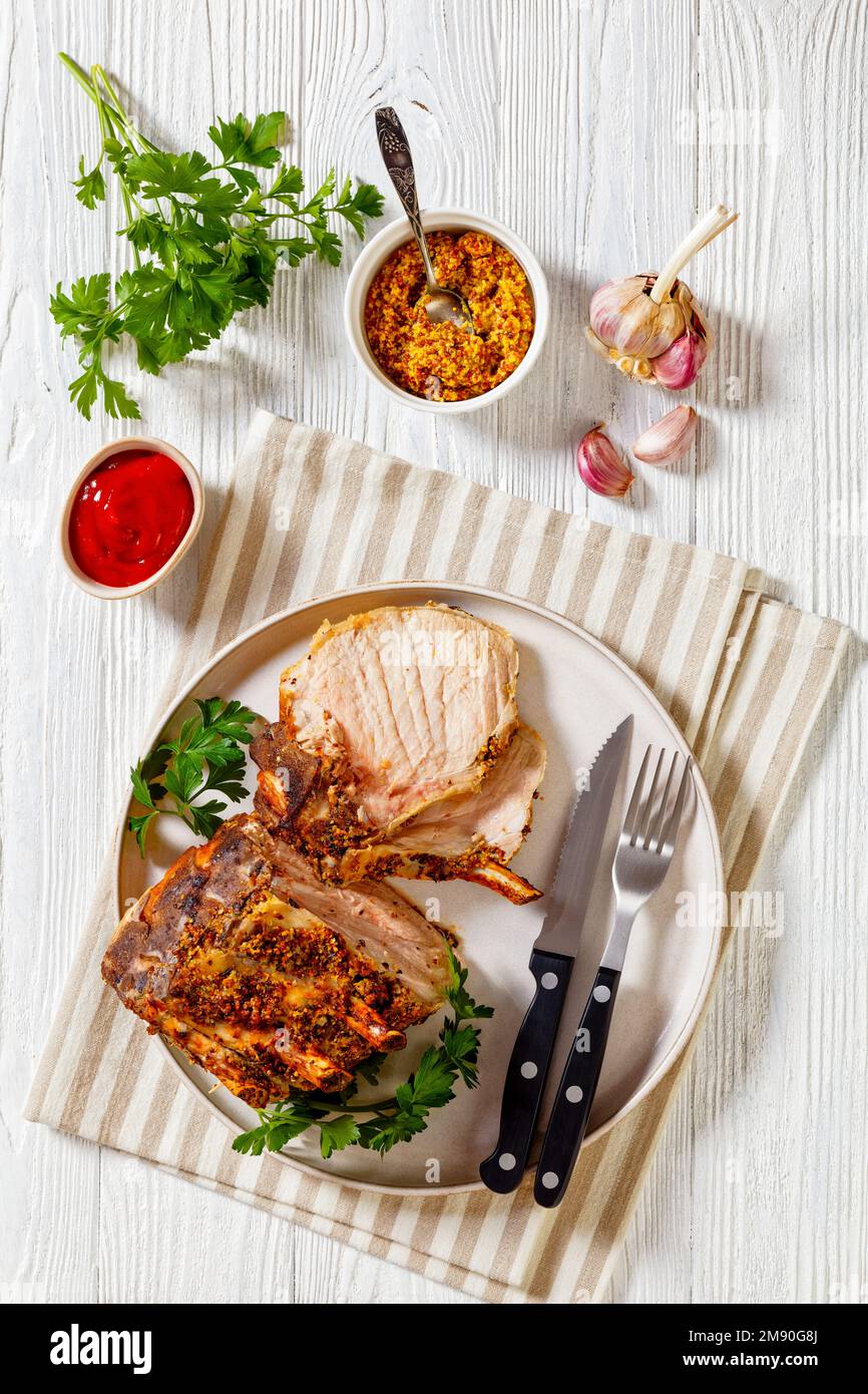 Standing Pork Rib Roast cut on chops with tomato sauce, mustard and ...