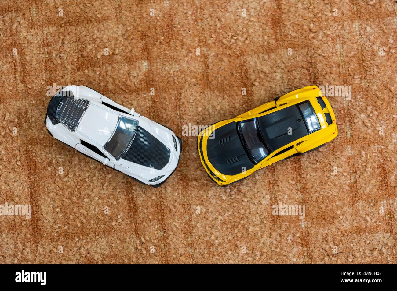 Two toy models of modern sports cars stand on brown carpet. View from ...