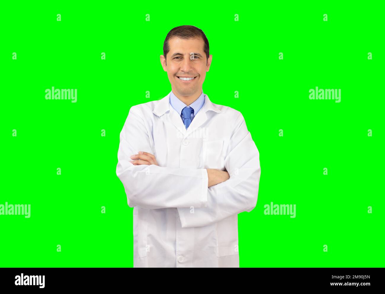 A handsome doctor standing with his arms folded and smiling at the ...