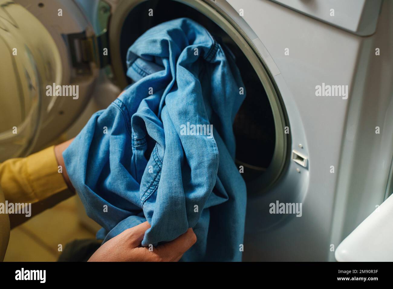 Woman loading clothes into washing machine Stock Photo - Alamy