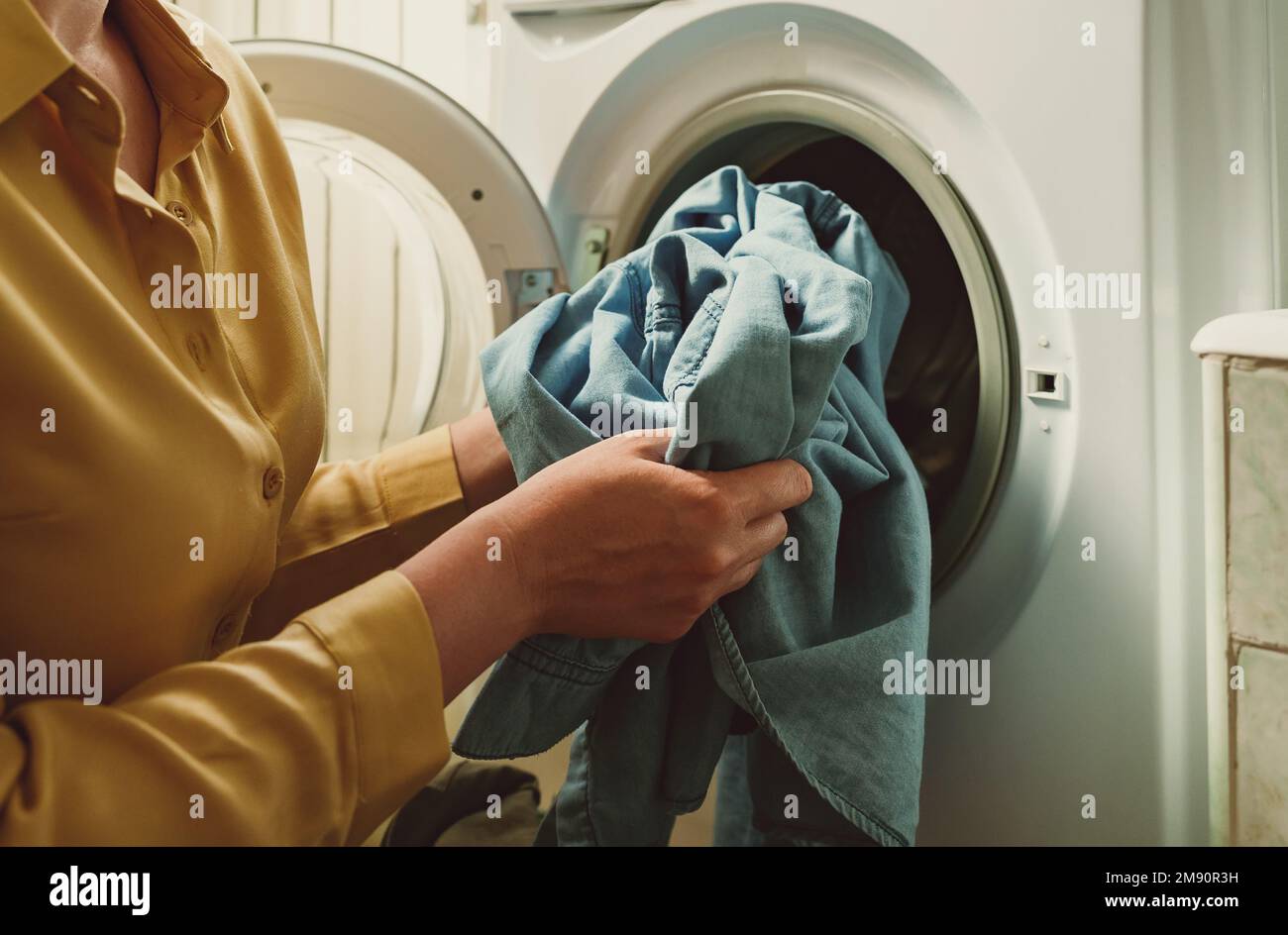 Woman loading clothes into washing machine Stock Photo - Alamy