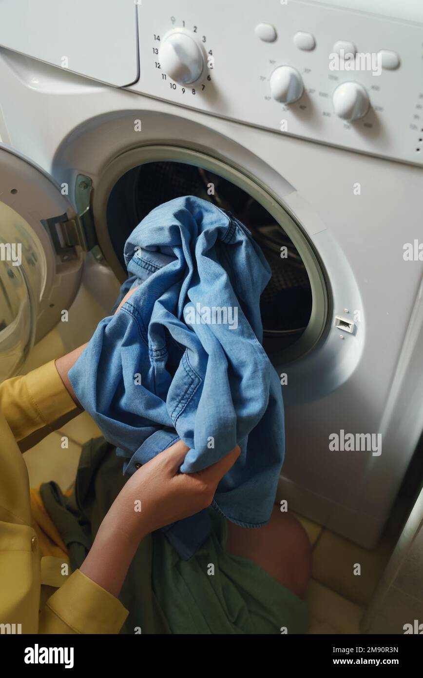 Woman loading clothes into washing machine Stock Photo - Alamy