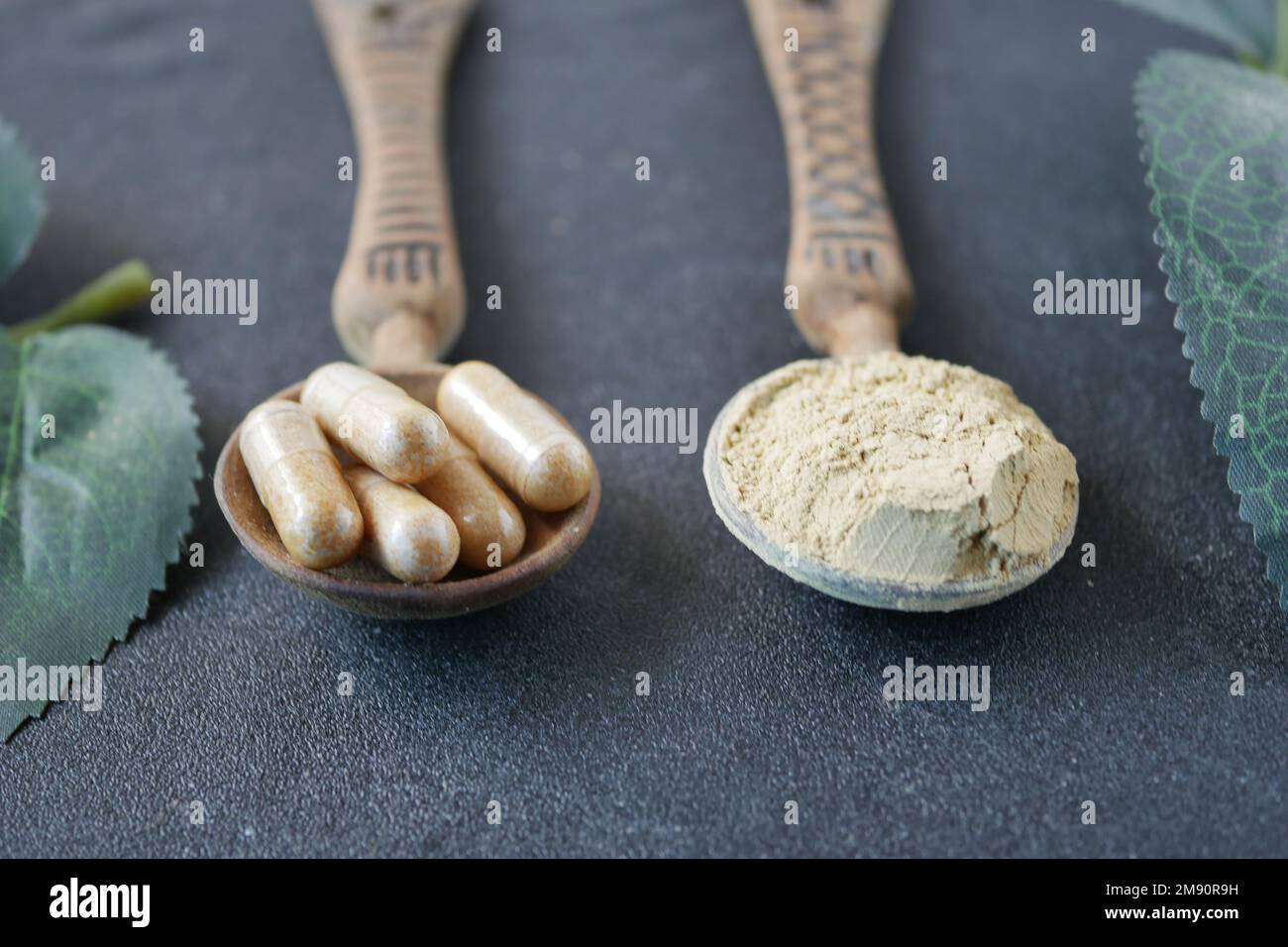 top view of herbal medicine capsule and powder on wooden spoon on white ...