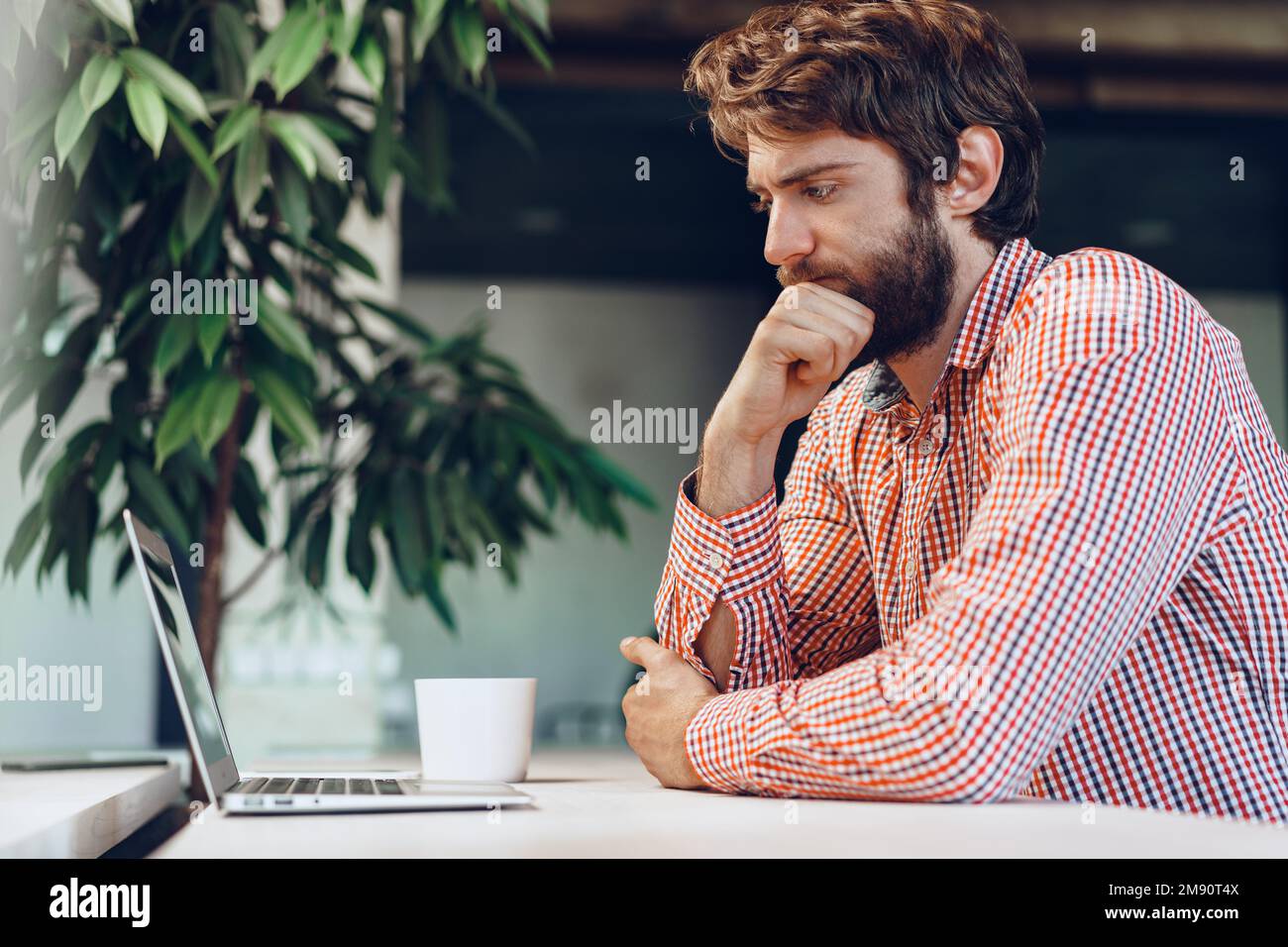 Puzzled thoughtful businessman sitting at his working table in an ...