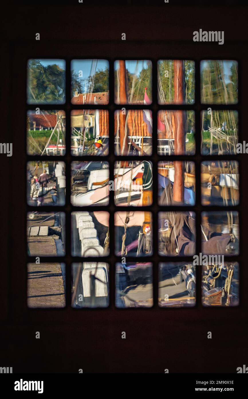 A wooden window with a vintage view of the old ship harbor outside ...