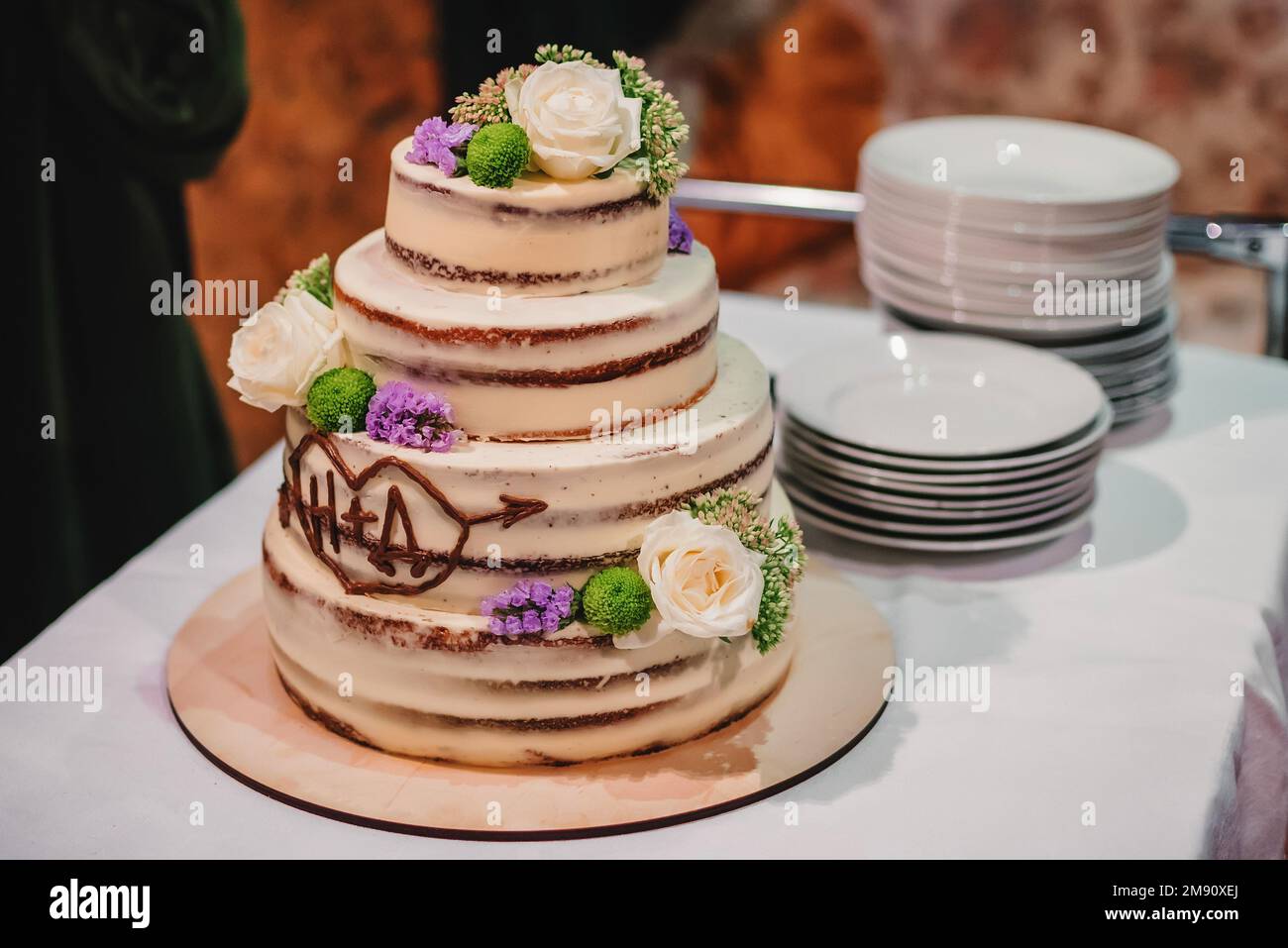sweet wedding cake with tiers decorated with flowers on white table ...