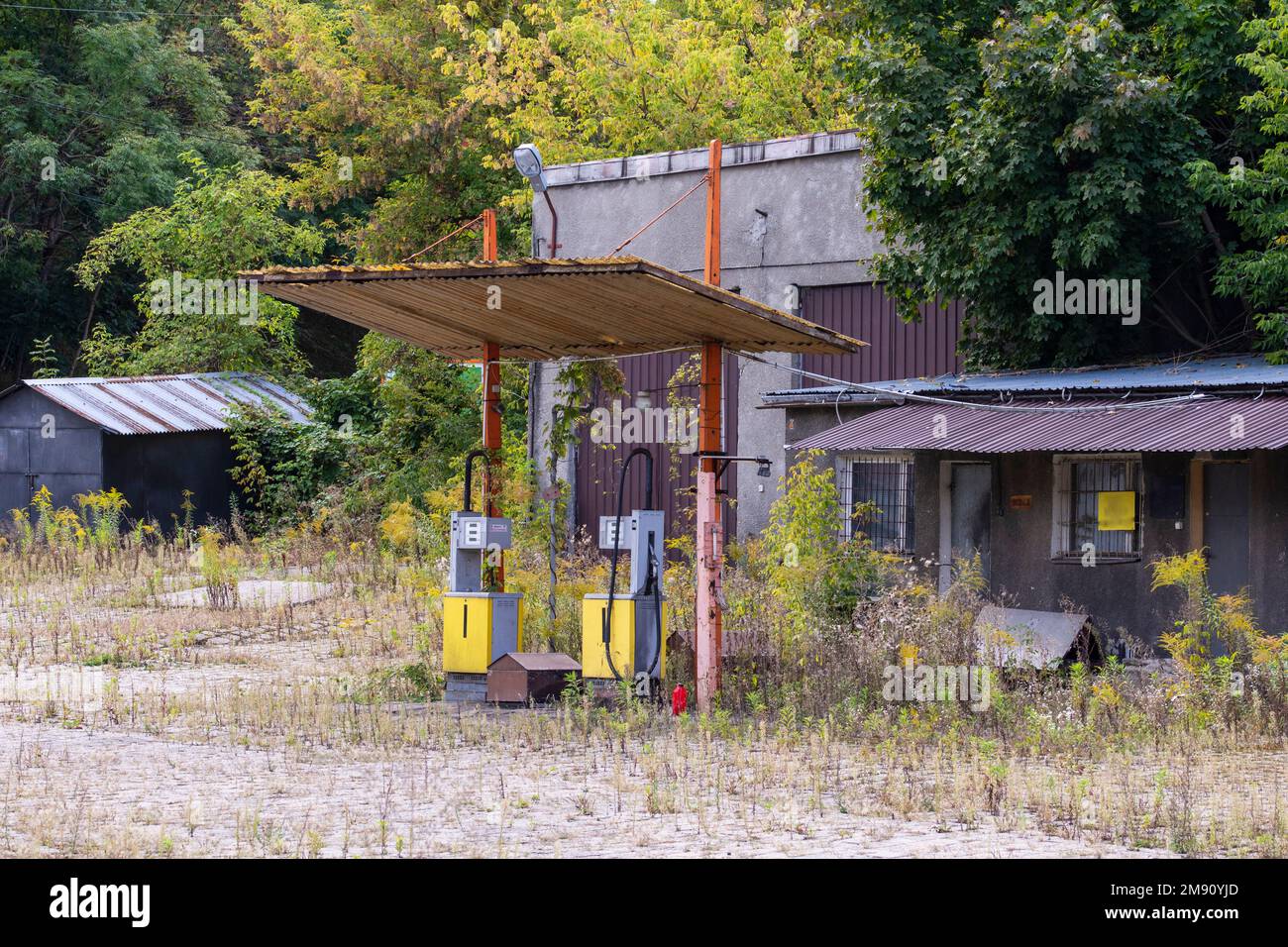 Old rusty gas station and dispensers abandoned and overgrown with ...