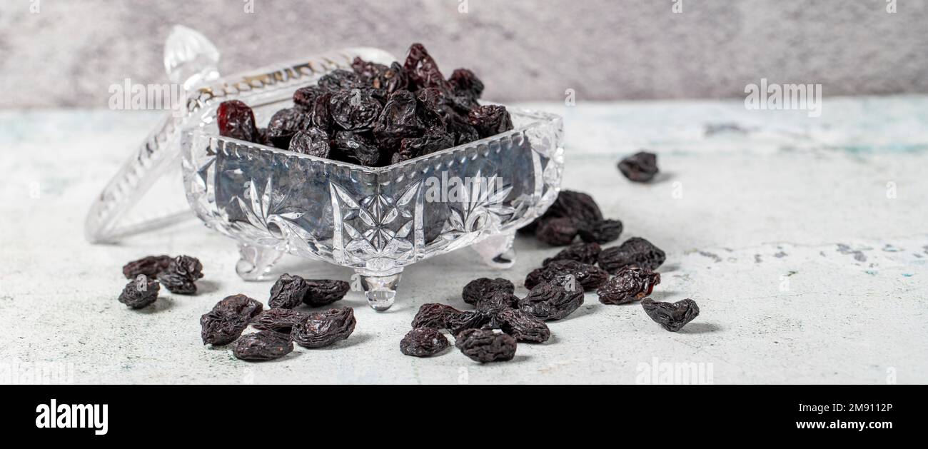 Dried black grapes on stone background. Dried grapes in glass bowl ...