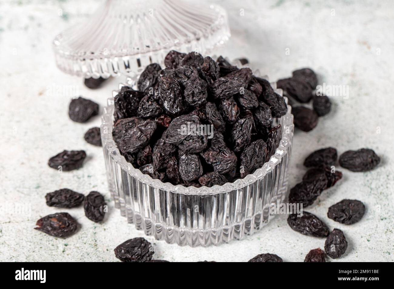 Dried black grapes on stone background. Dried grapes in glass bowl ...