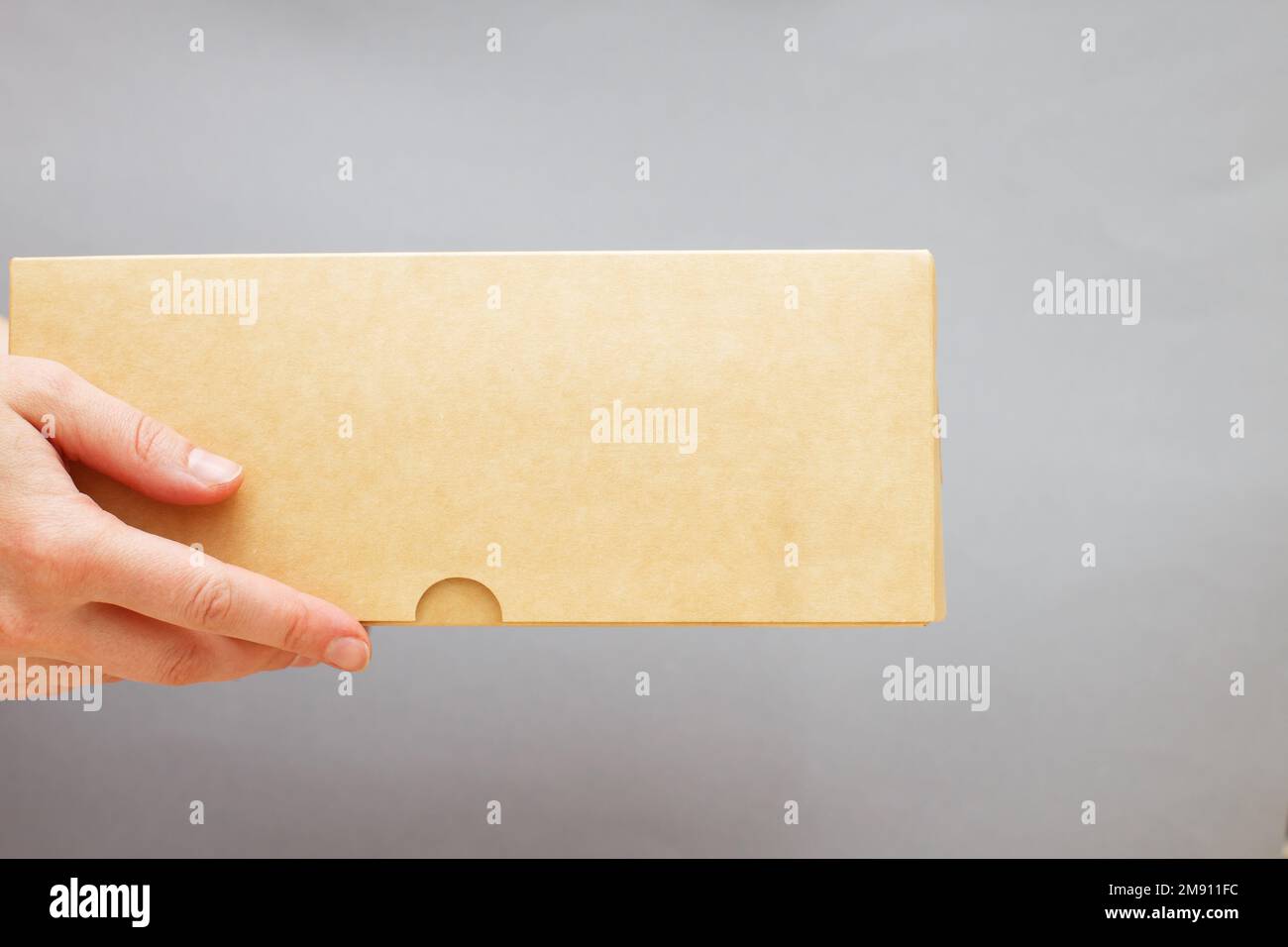 The human hands holding delivers carton box on the grey background ...