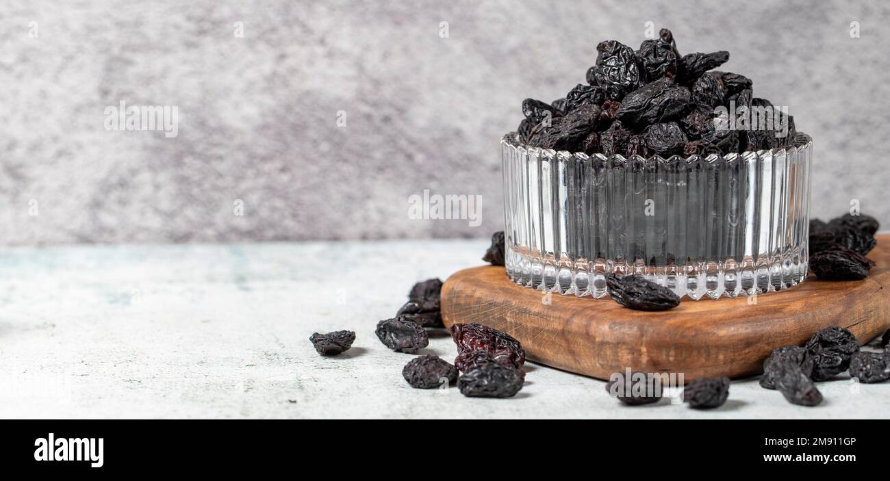 Dried black grapes on stone background. Dried grapes in glass bowl ...