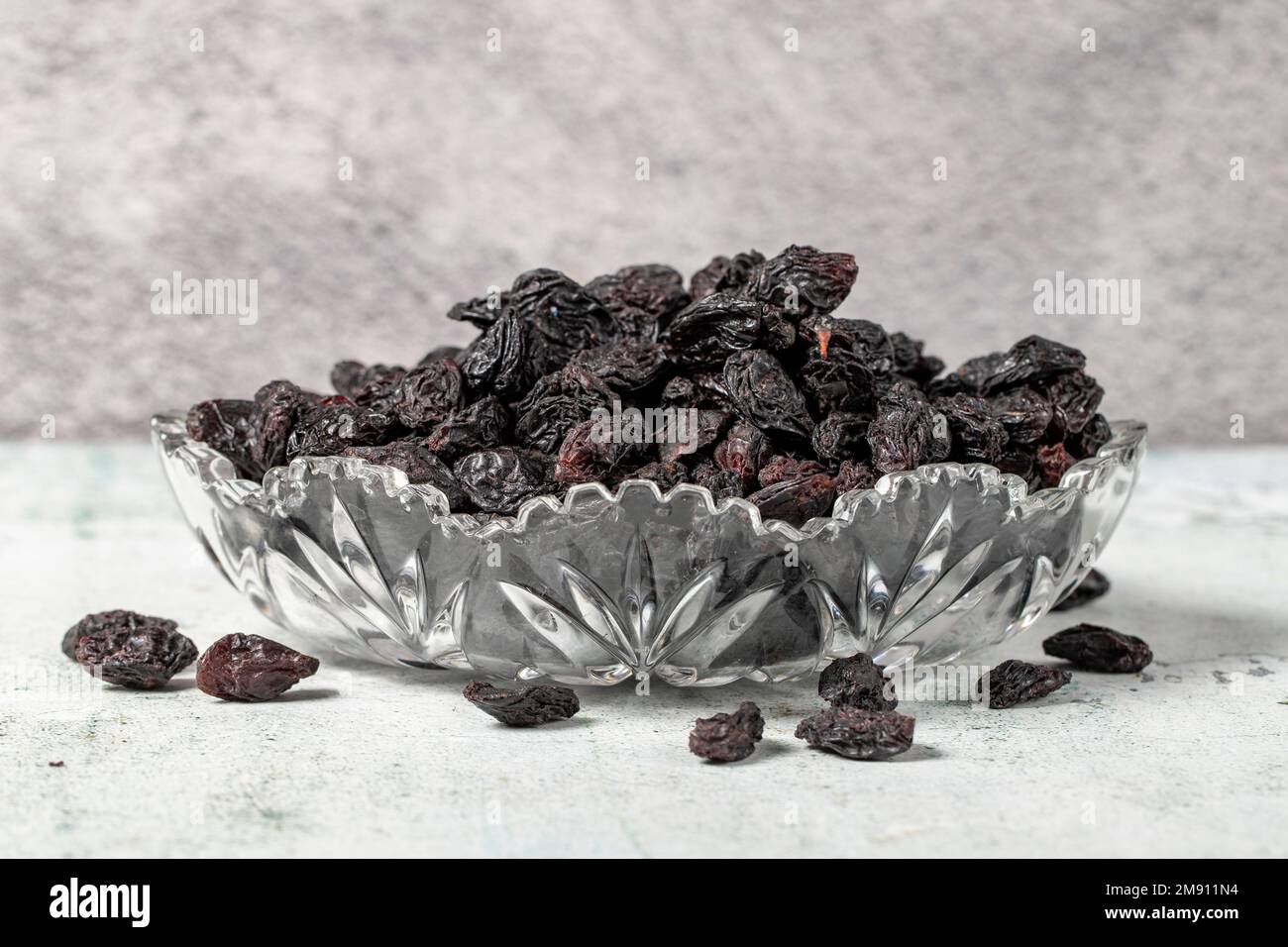 Dried black grapes on stone background. Dried grapes in glass bowl ...