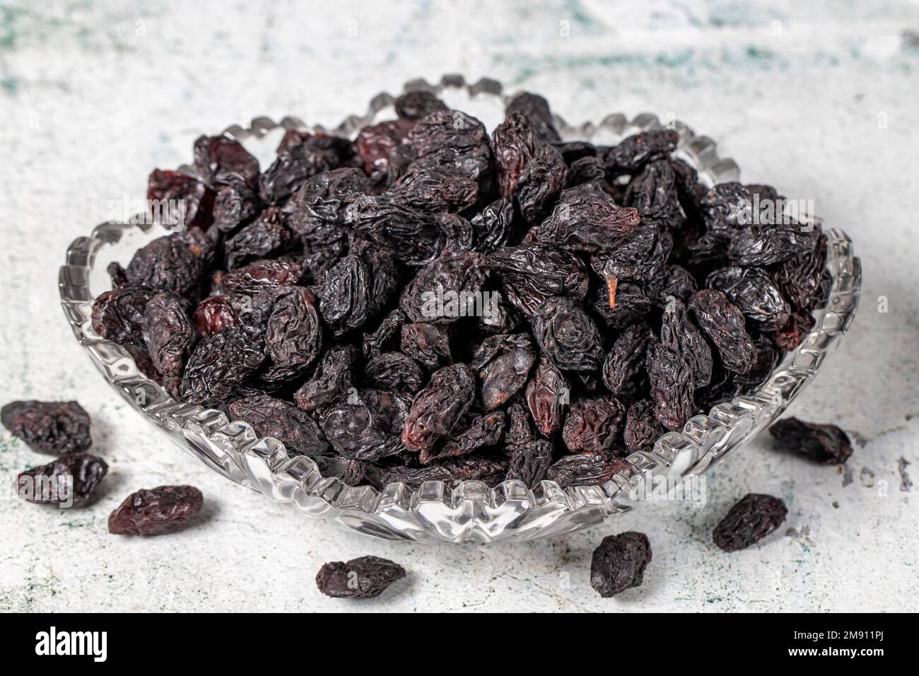 Dried black grapes on stone background. Dried grapes in glass bowl ...