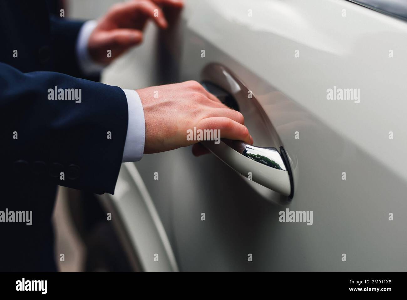 man in the suit opens the car door. Hand close up Stock Photo - Alamy
