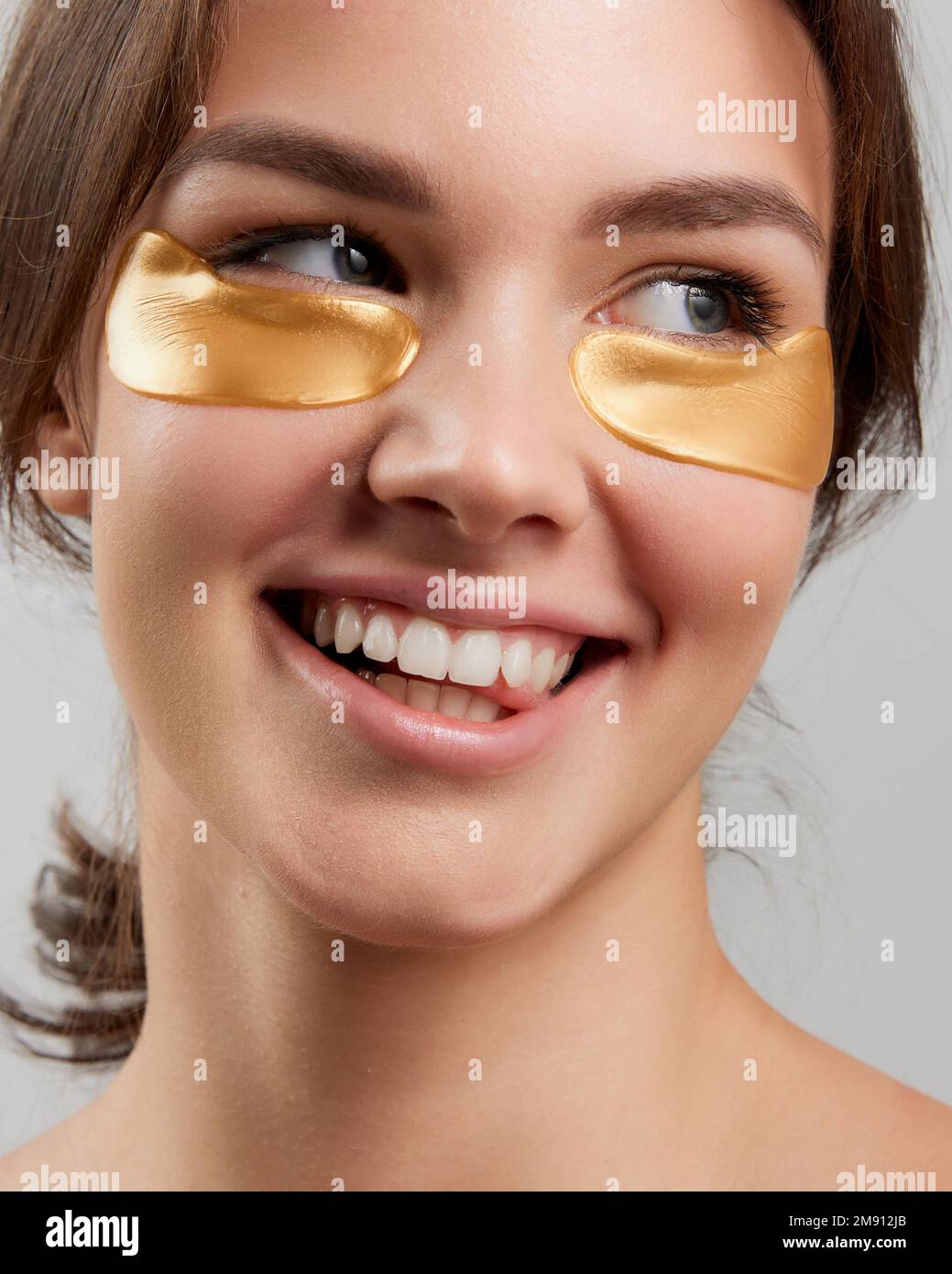 Smiling young beautiful girl with well-kept skin doing face cosmetology ...