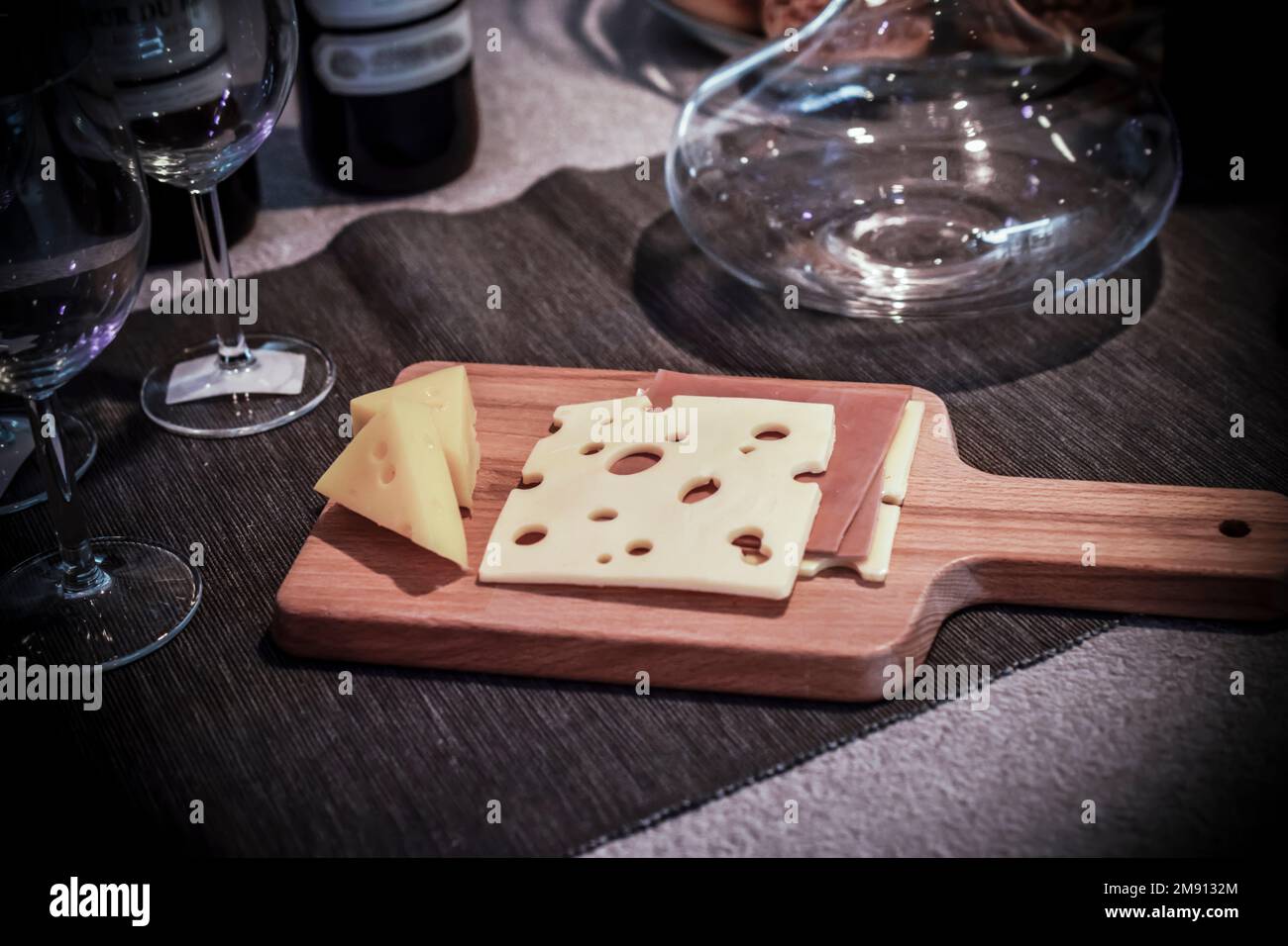 A detail of a kitchen table with a wooden cheese board and a partial ...