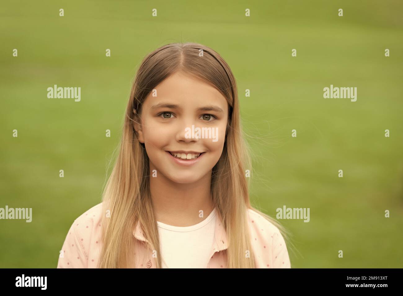 Portrait of happy girl child smiling on green grass background outdoors ...