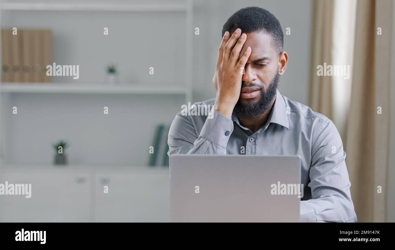 Stressed disappointed African American ethnic bearded man holding head ...