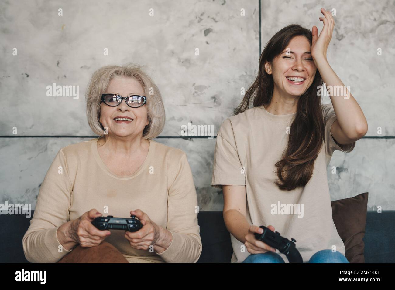 Senior mother and dughter playing video game together at home sitting ...