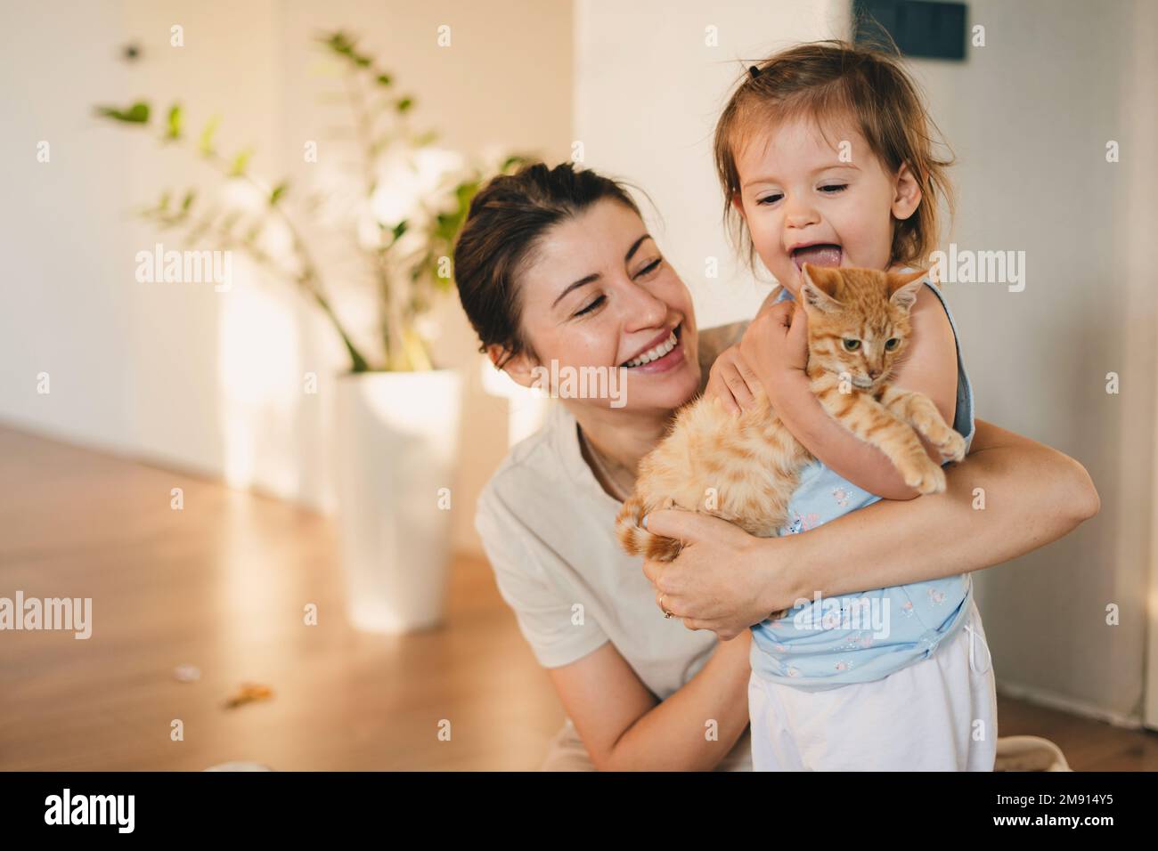 Beautiful woman with her baby girl at home holding and hug her lovely ...