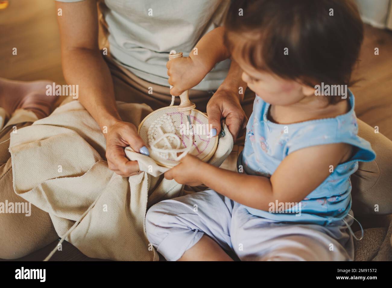 Mother and child daughter together embroider on the canvas. Woman ...