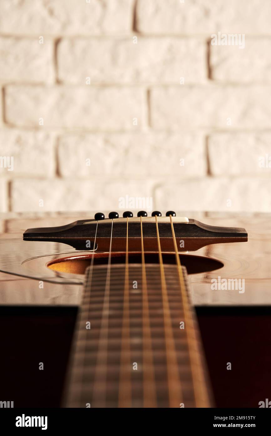 Perspective view of an acoustic guitar and its strings and white bricks ...
