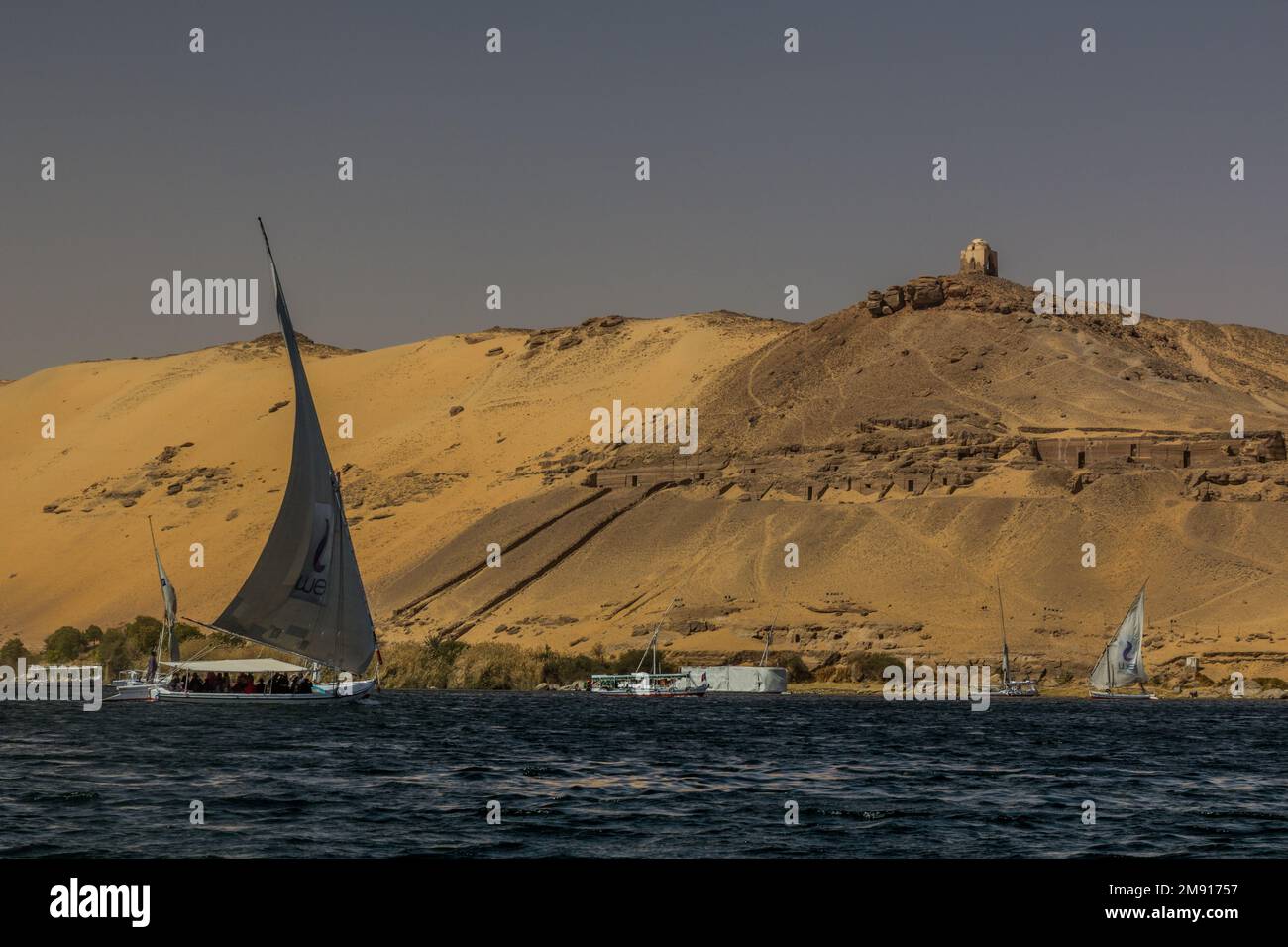 ASWAN, EGYPT: FEB 15, 2019: Felucca sail boats under the Qubbet el-Hawa ...