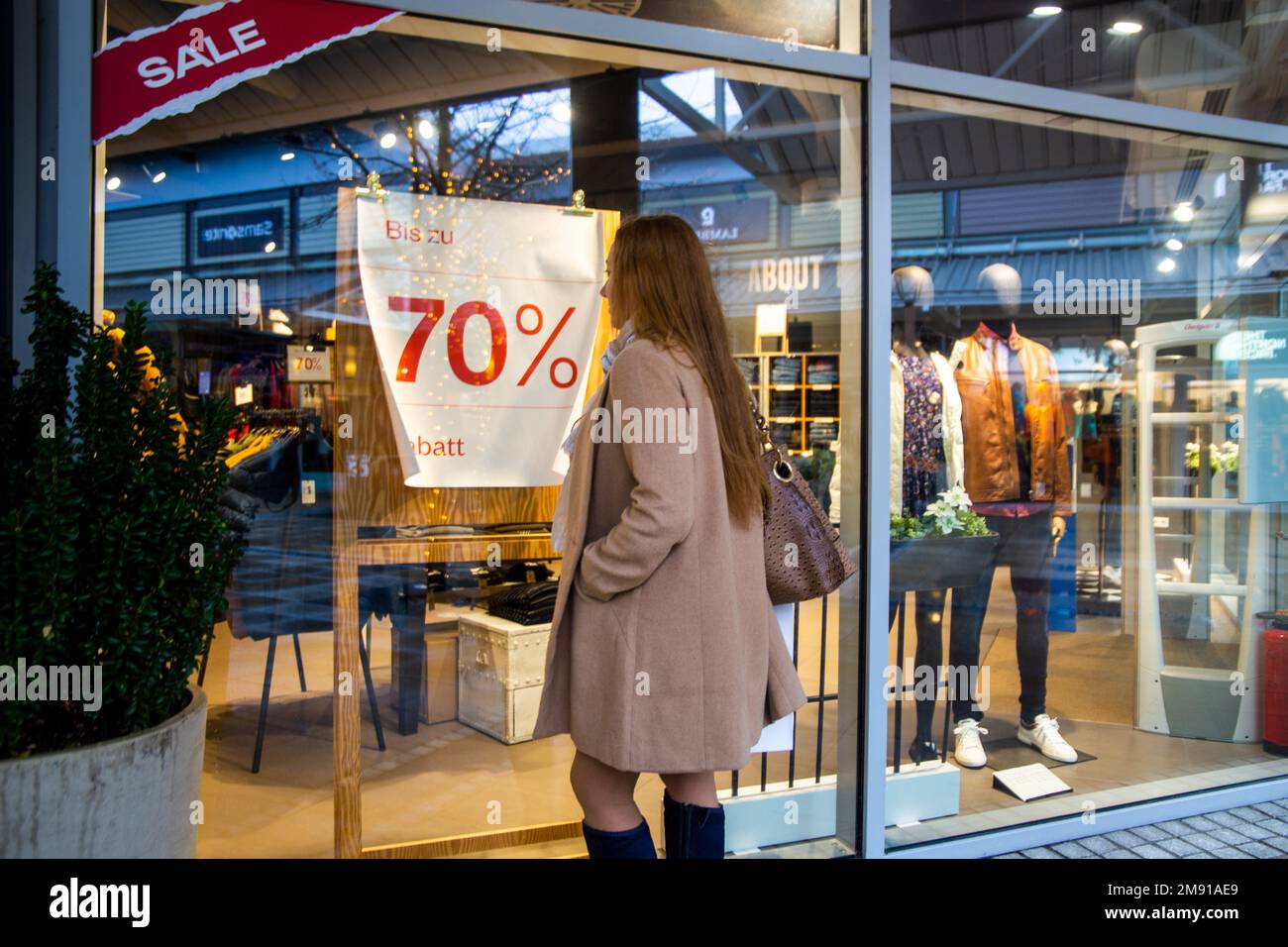 Retail discounts: Young woman standing in front of the window of a ...