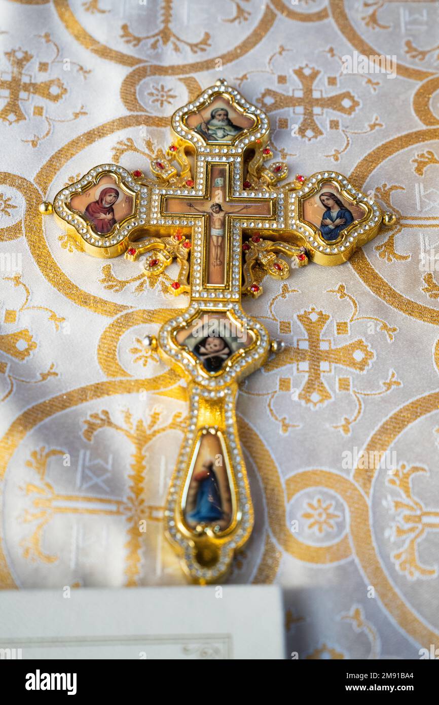 A vertical closeup of a golden cross with Jesus Christ and icons of ...