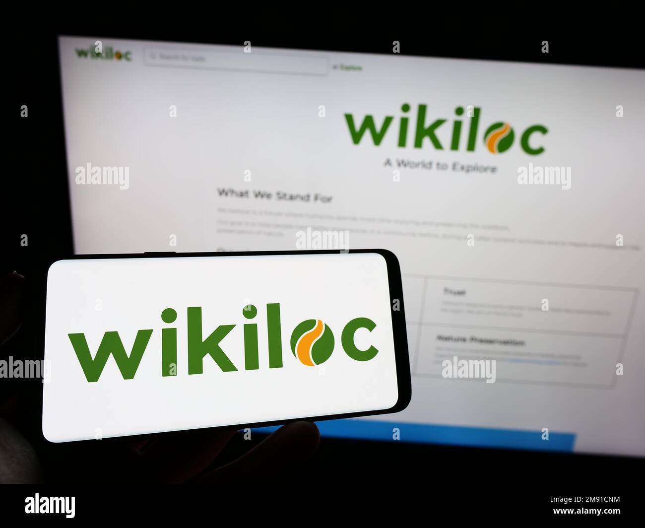 Person holding mobile phone with logo of GPS trail company Wikiloc ...