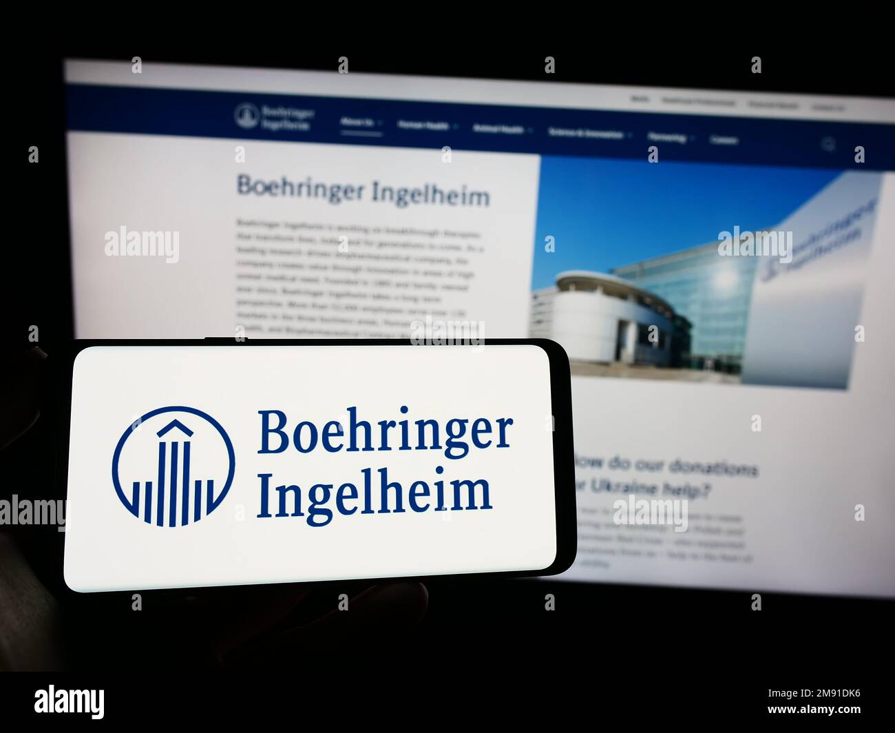 Person holding mobile phone with logo of pharmaceutical company ...