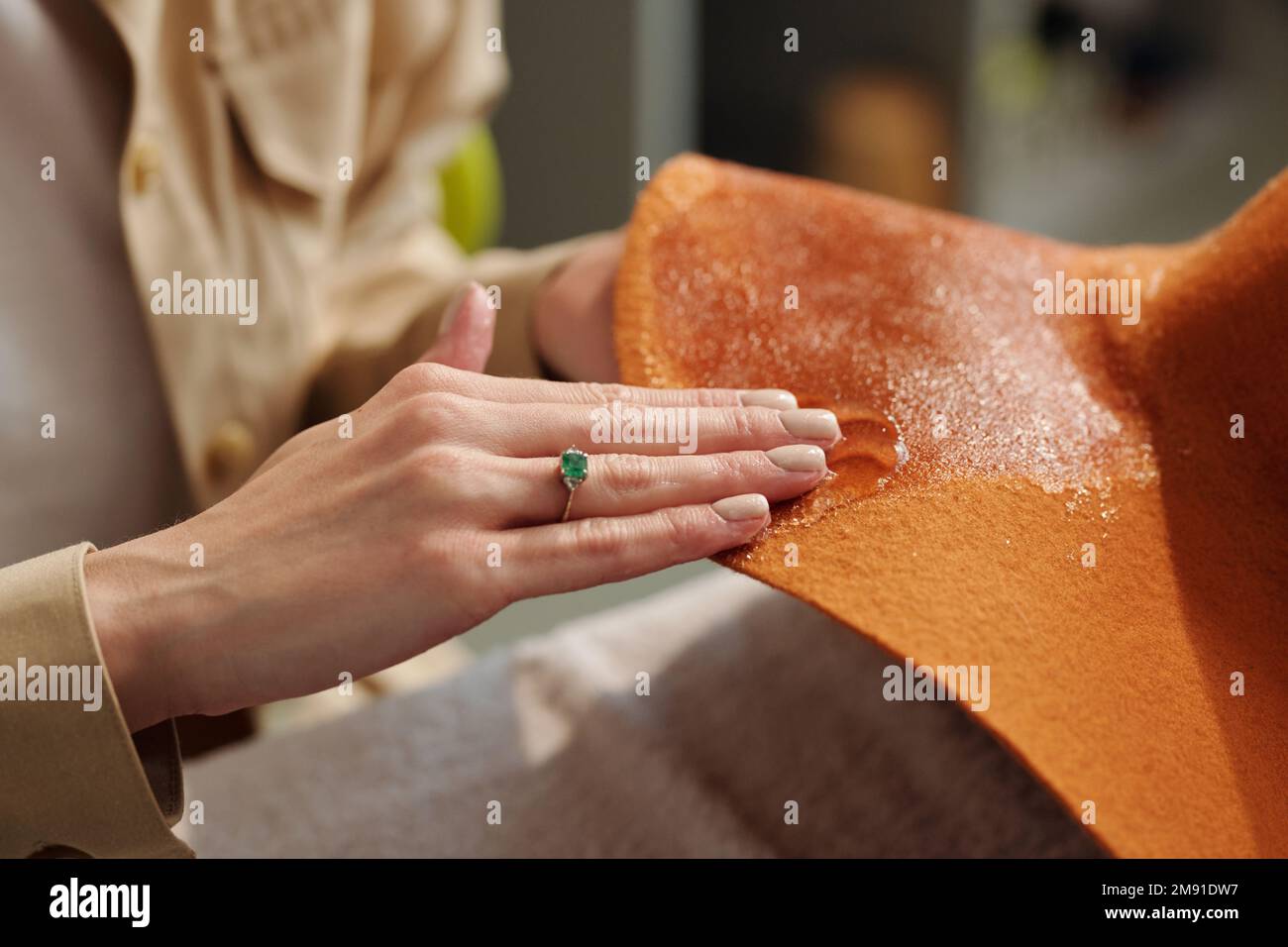 Close-up of hand of young creative female designer applying fixing gel ...