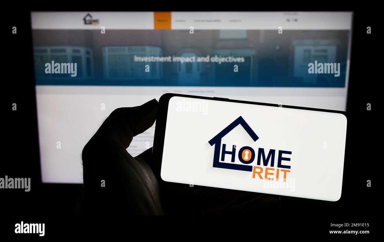 Person holding cellphone with logo of British real estate company Home ...