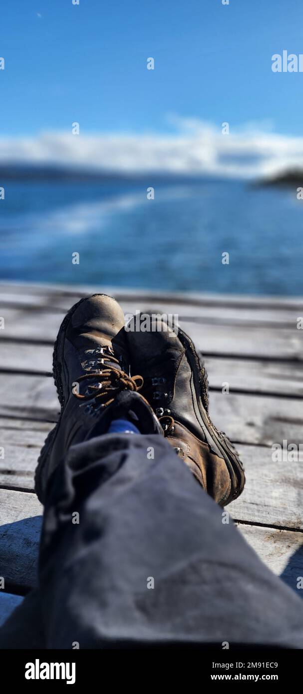 A vertical shot of the feet of a human with dark brown shoes sitting on ...