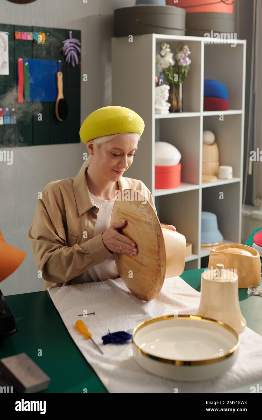 Young craftswoman or apparel designer putting together two parts of ...