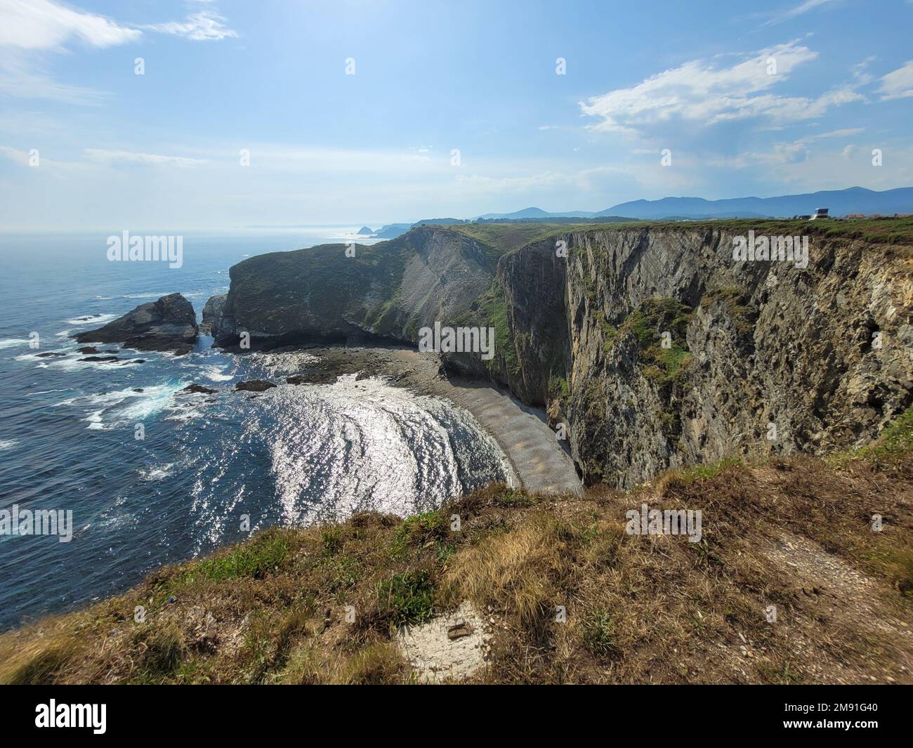An aerial view of steep rock formations overlooking the sea under blue ...