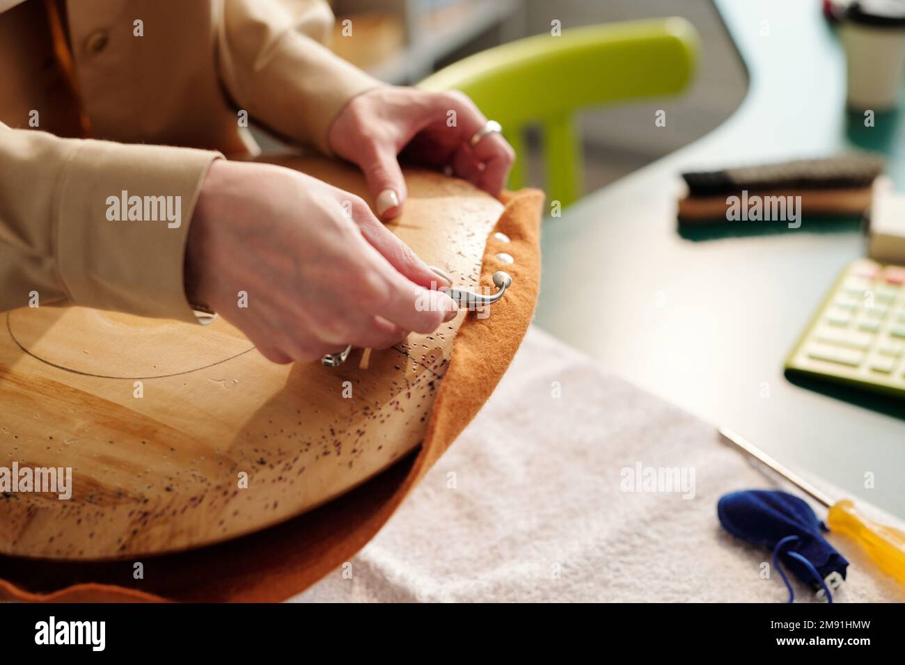 Close-up of craftswoman fixing edges of hat brim with pins to special ...