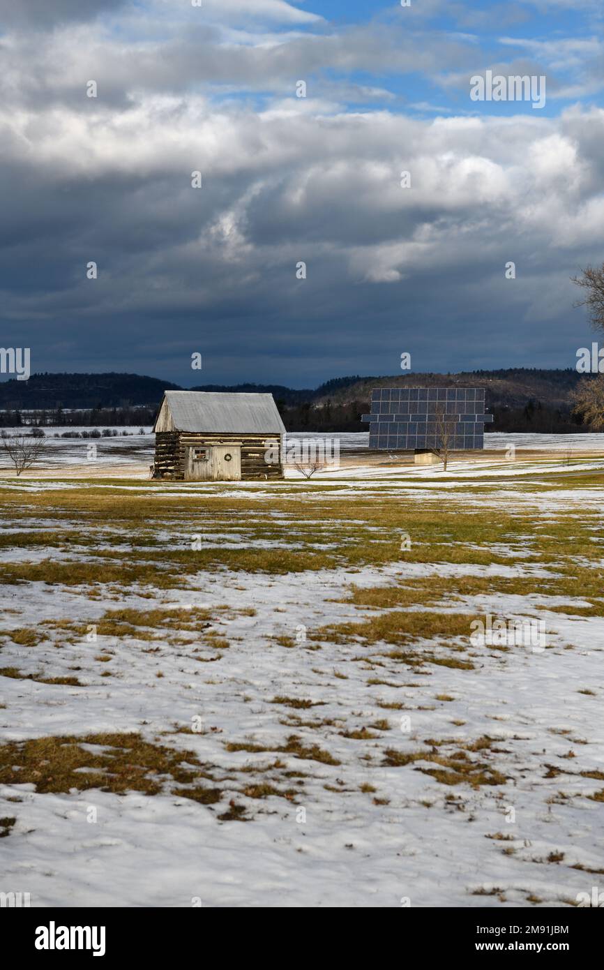One room log cabin shack with solar panel in farmers field with snow ...