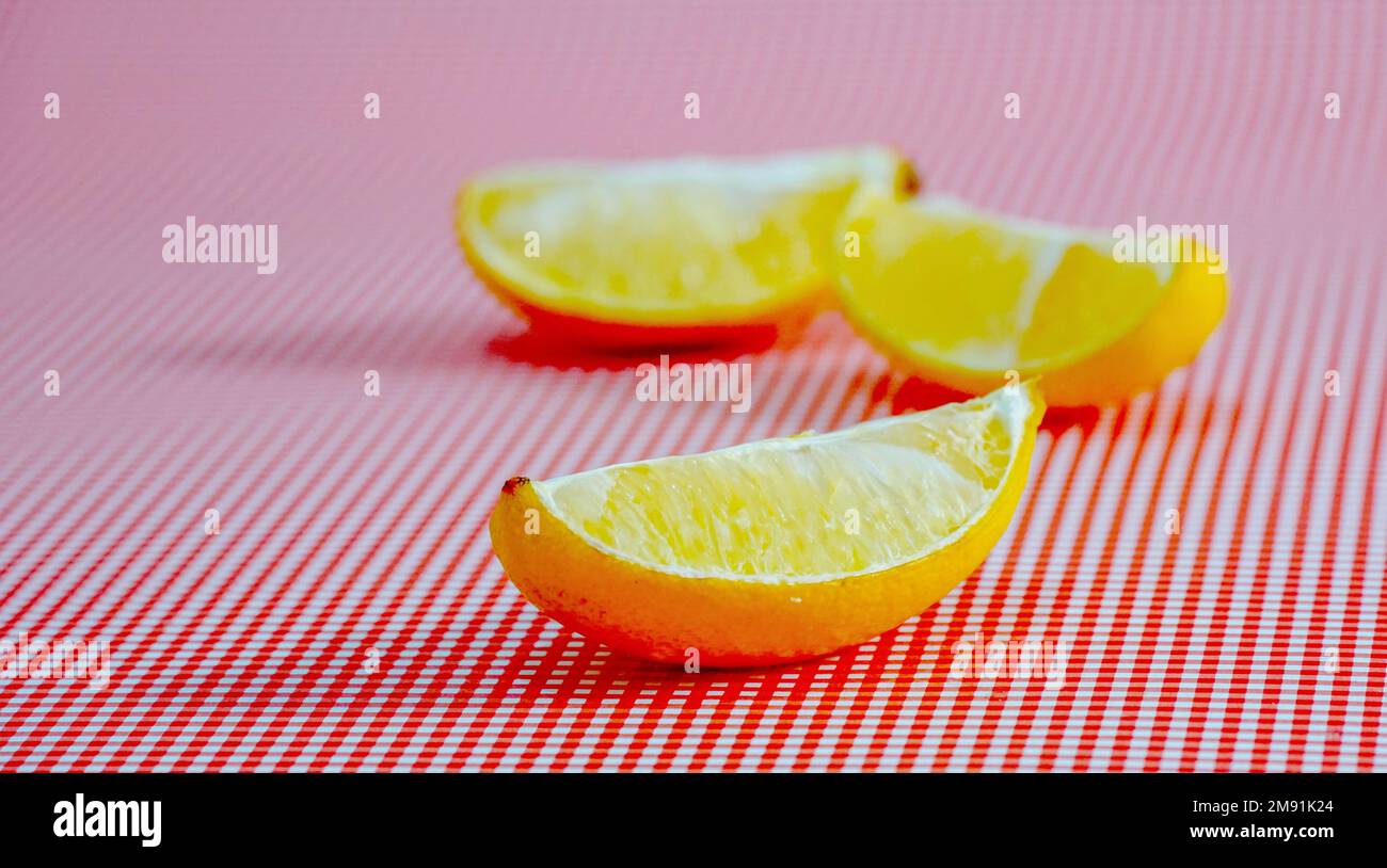 slices of lemon citrus fruit on pink stripped background. Lemon slice ...