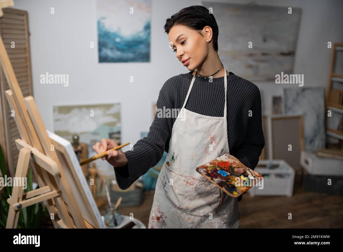 Brunette short haired artist painting on canvas in studio Stock Photo ...